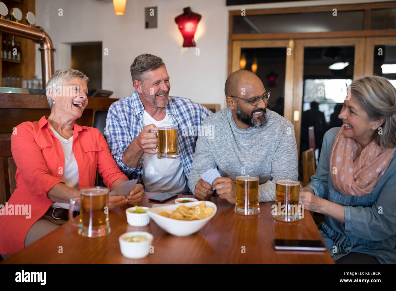Happy friends interacting while having beer and snacks in bar Stock ...