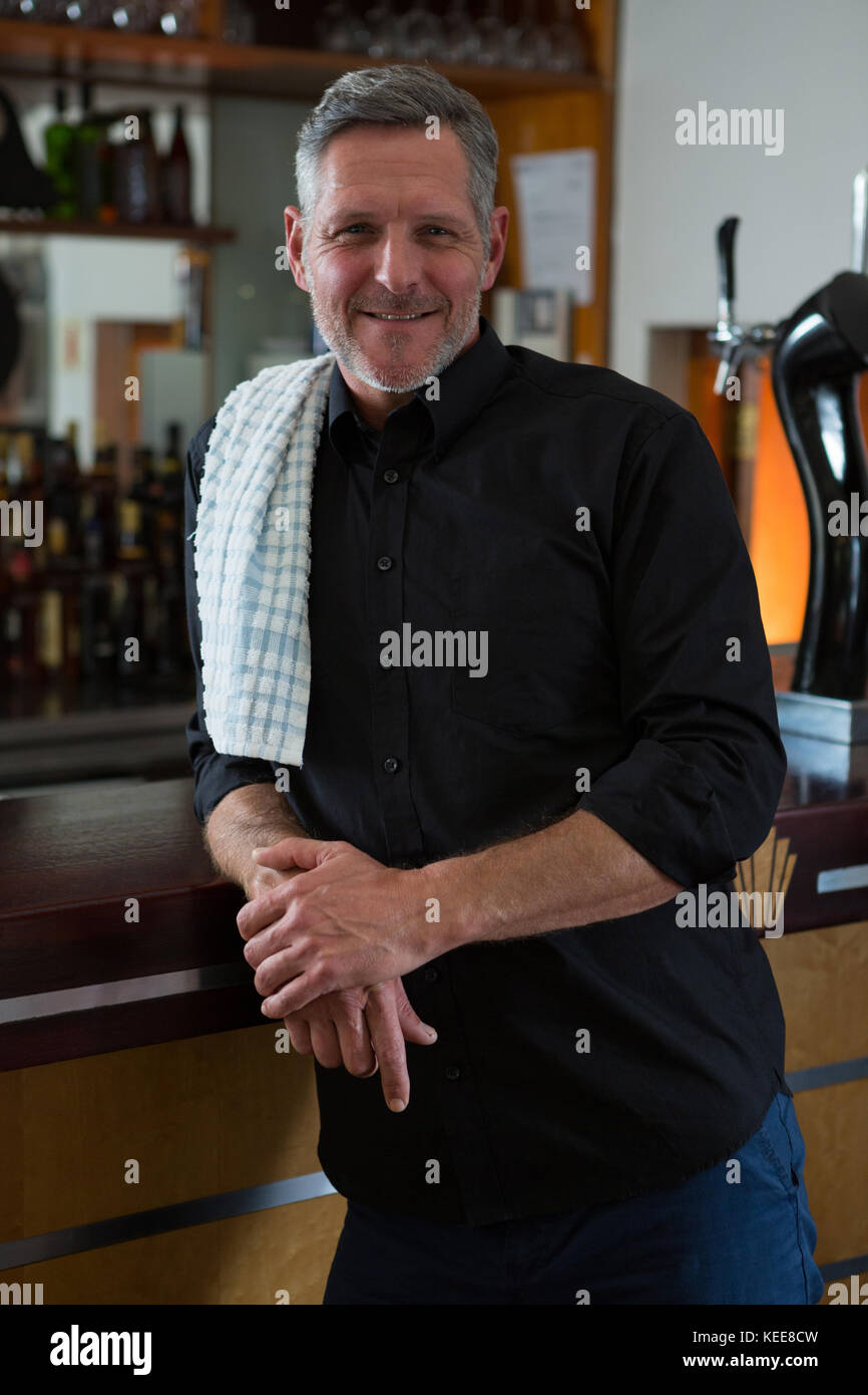 Portrait of happy bar tender leaning at bar counter Stock Photo - Alamy