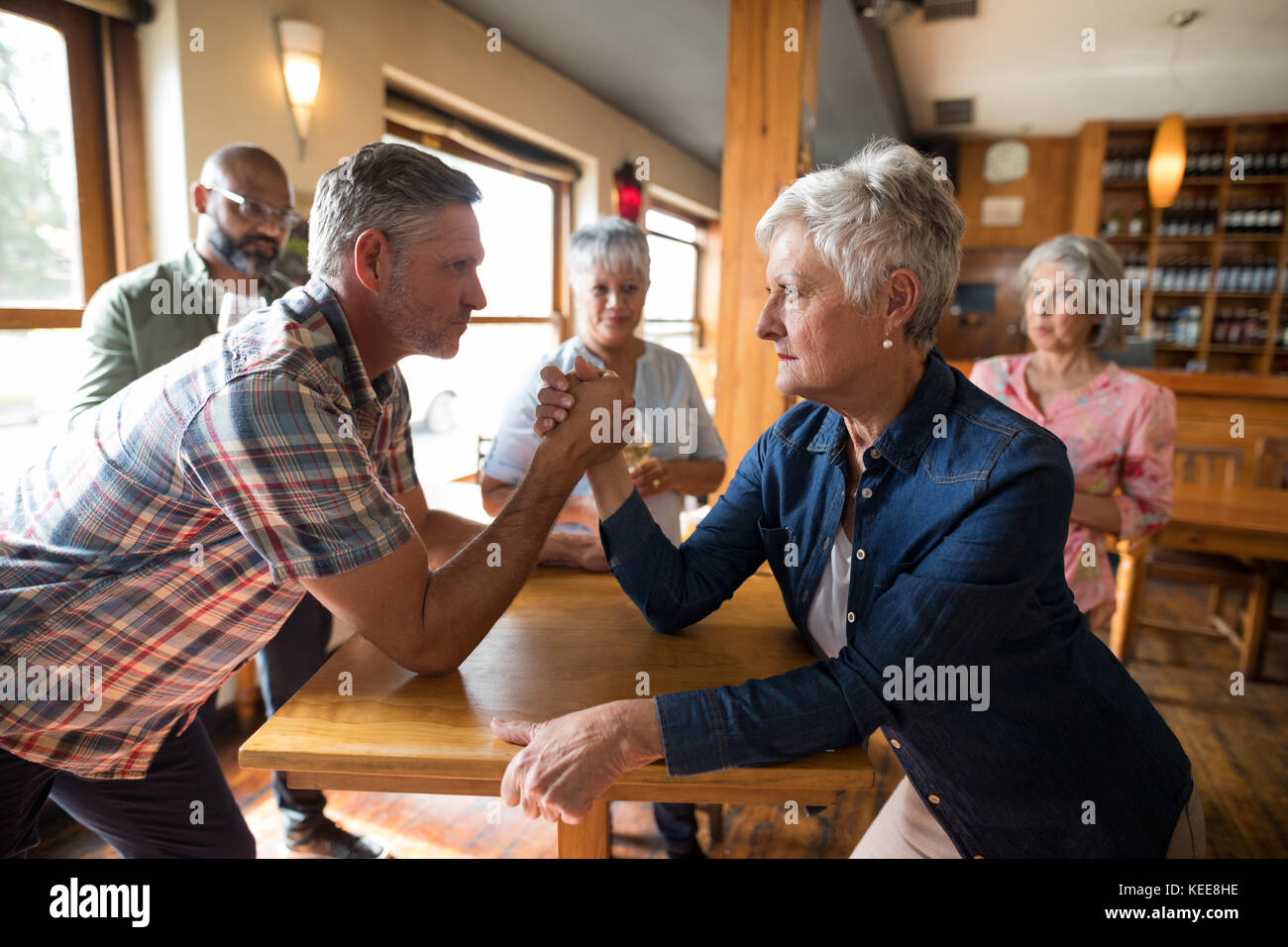 Friends arm wrestling each other in a bar Stock Photo - Alamy