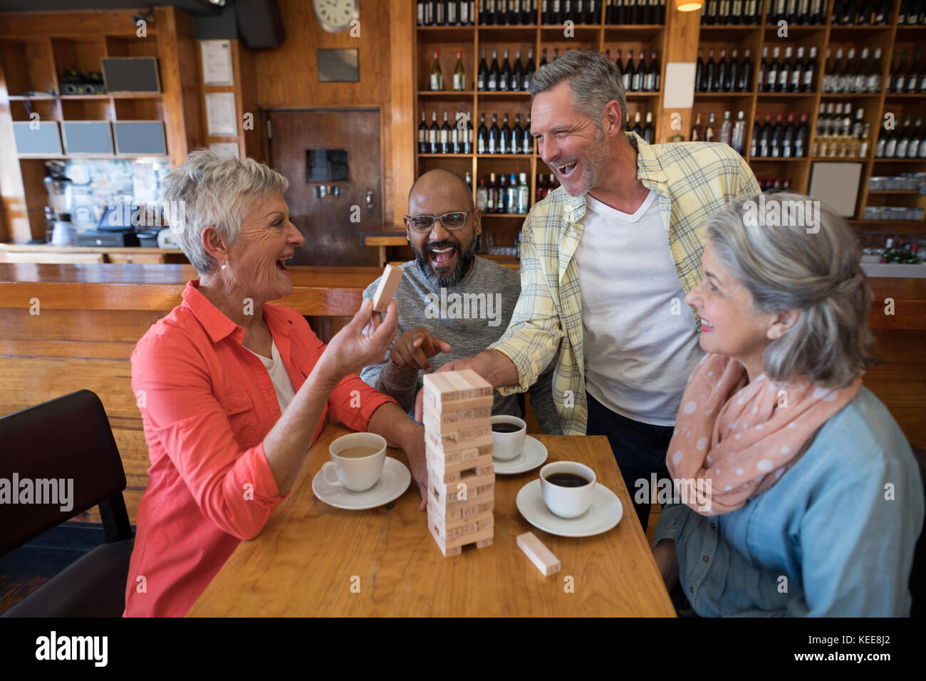 Happy friends playing jenga game while having cup of coffee in bar ...