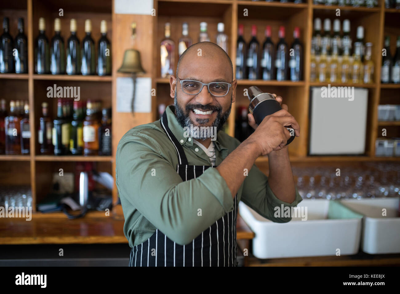 Portrait of smiling waiter shaking cocktail at bar counter in bar Stock ...