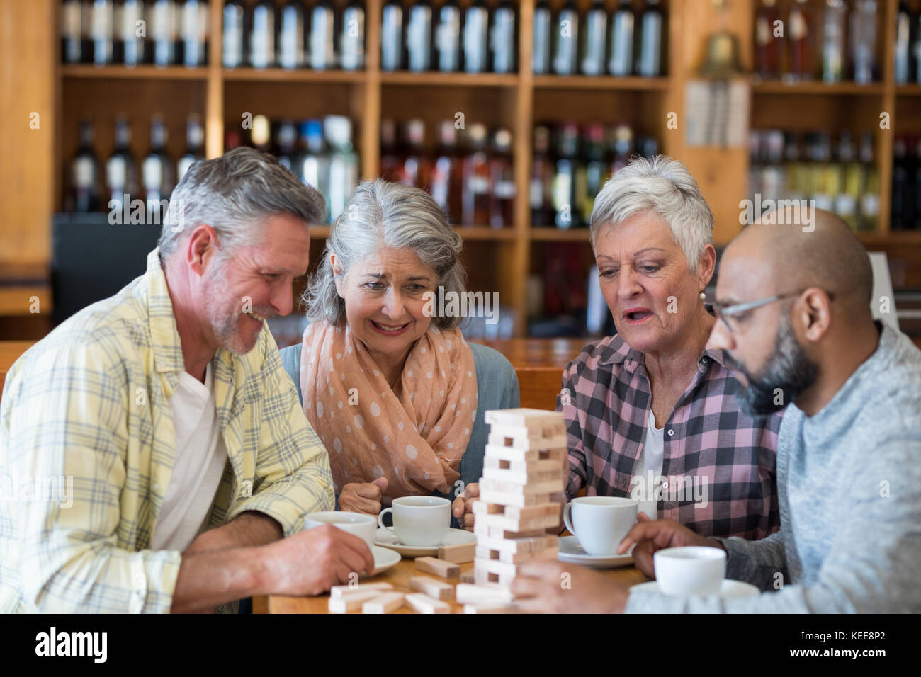Happy friends playing jenga game while having cup of coffee in bar ...
