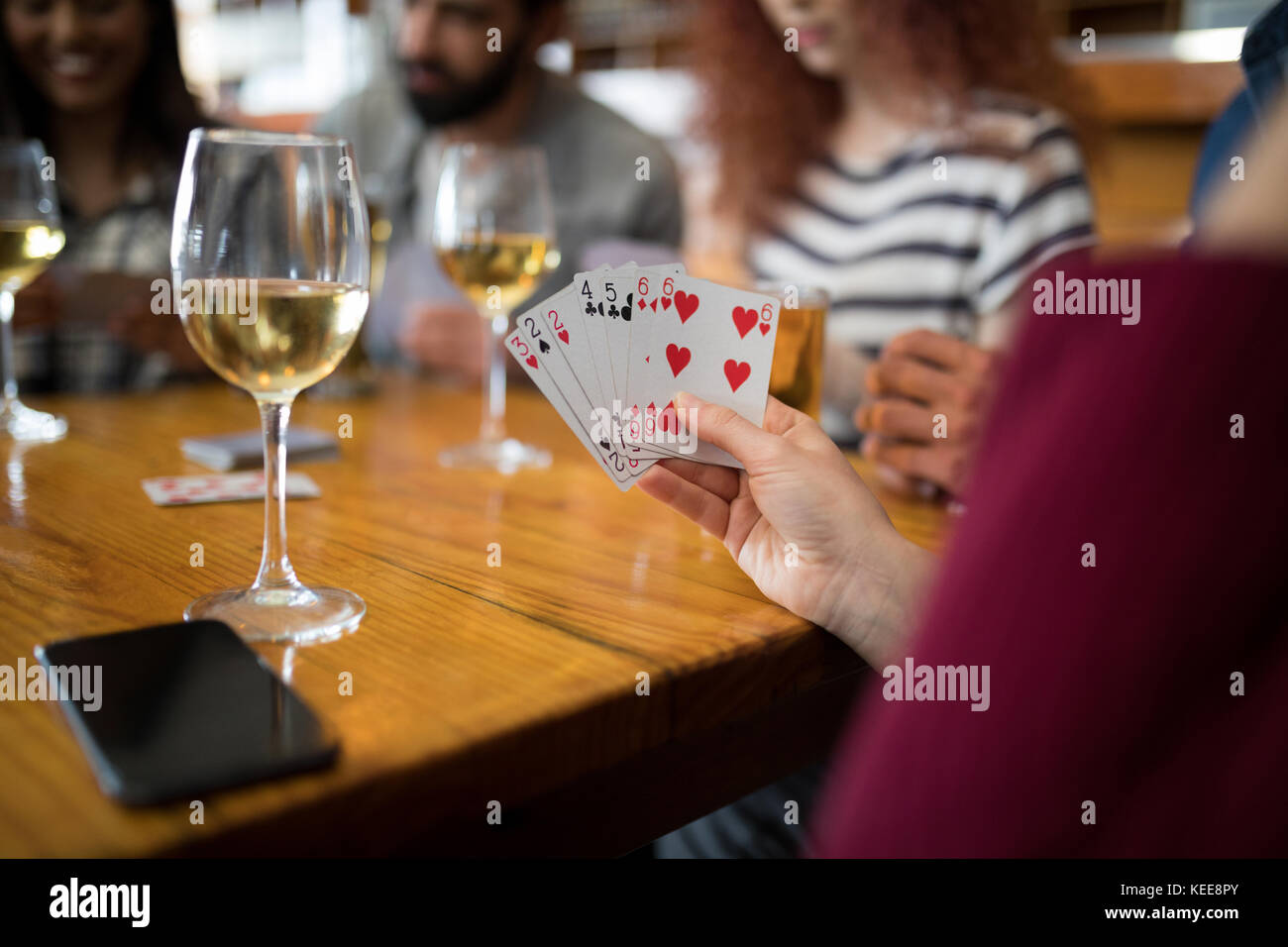 Mid section of friends playing cards in bar Stock Photo - Alamy