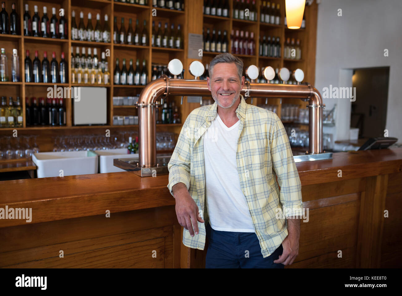 Portrait of happy man standing at counter in bar Stock Photo - Alamy