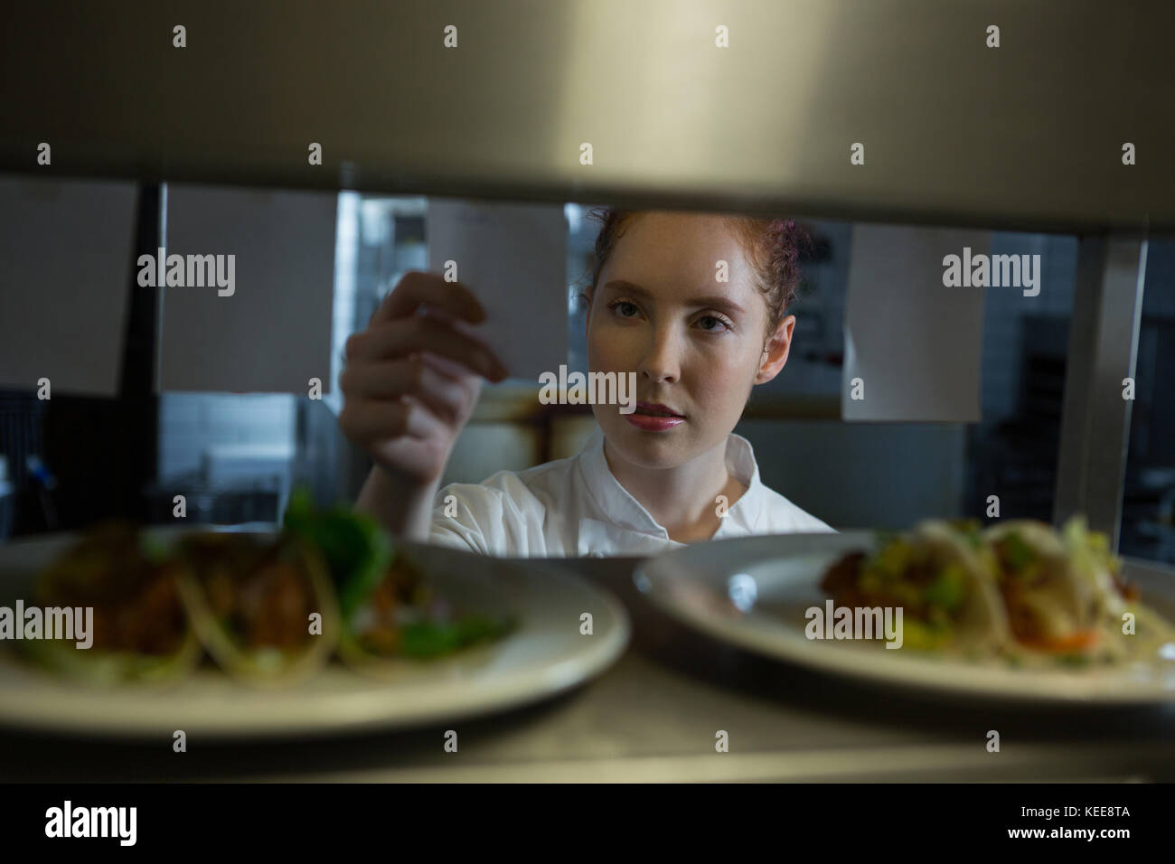 Female chef reading order in the kitchen Stock Photo - Alamy