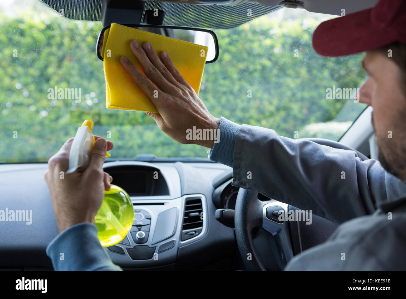 Male auto service staff cleaning rear view mirror in car Stock Photo ...