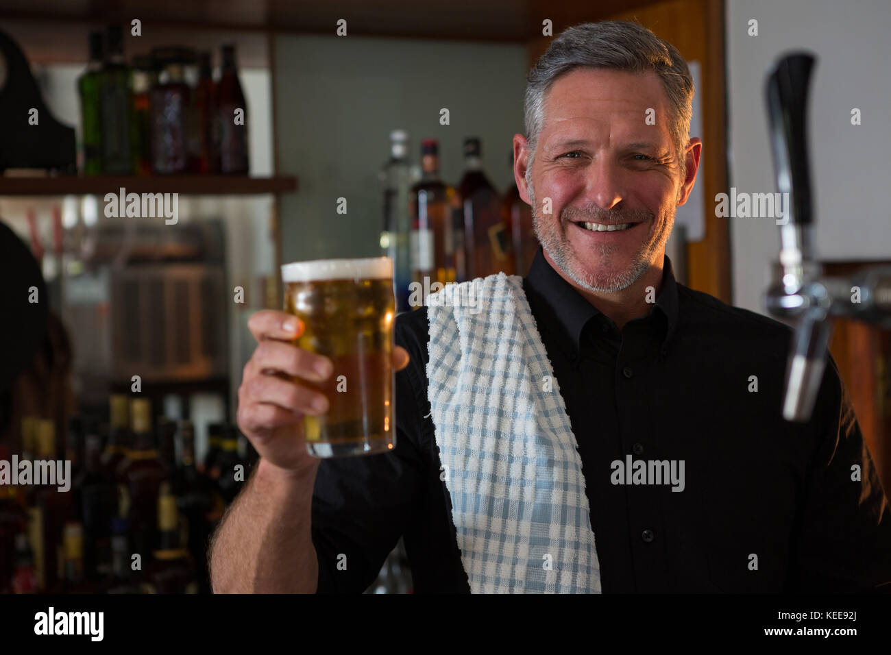 Portrait of happy bar tender offering beer at bar Stock Photo - Alamy