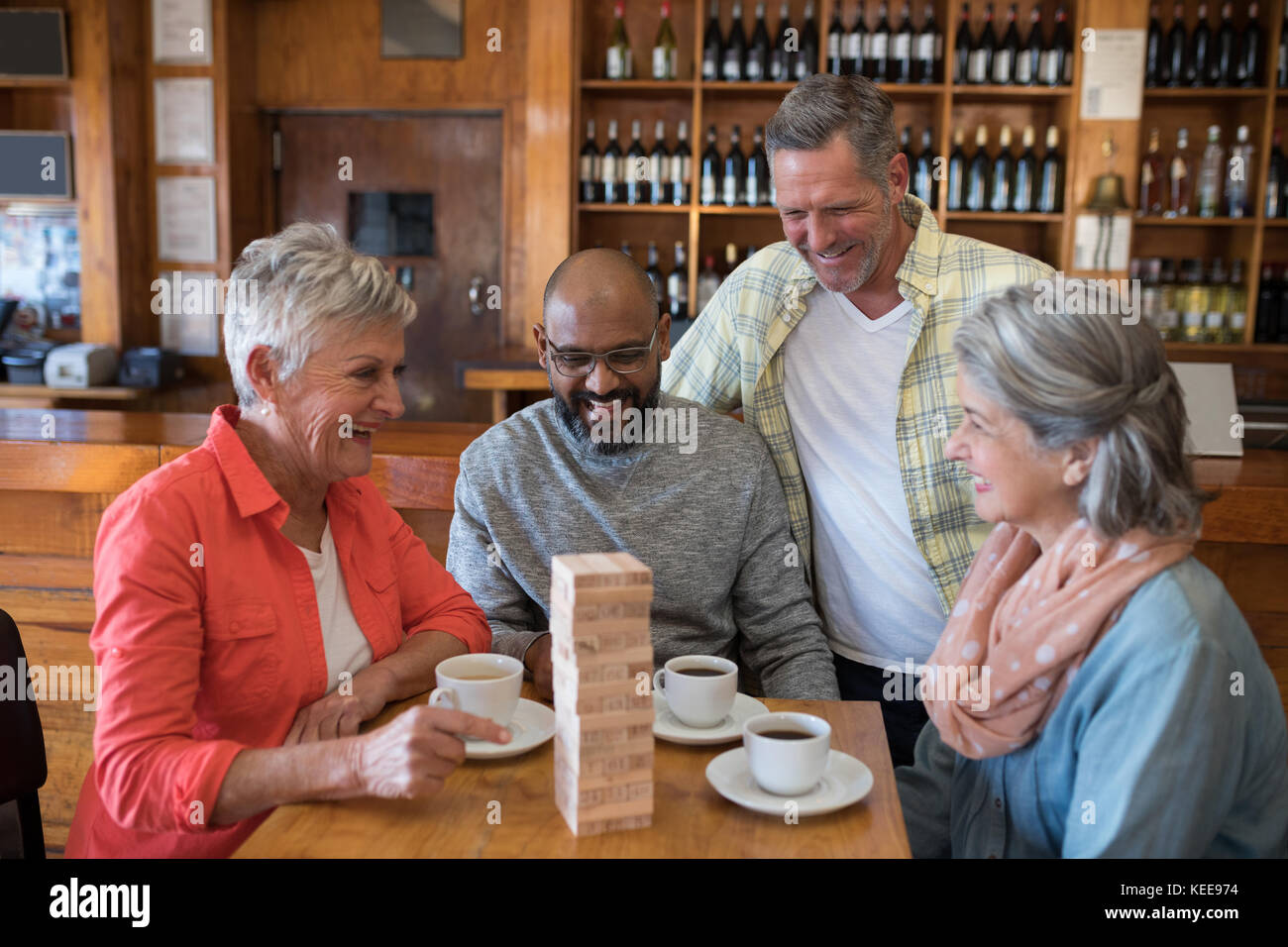 Happy friends playing jenga game while having cup of coffee in bar ...
