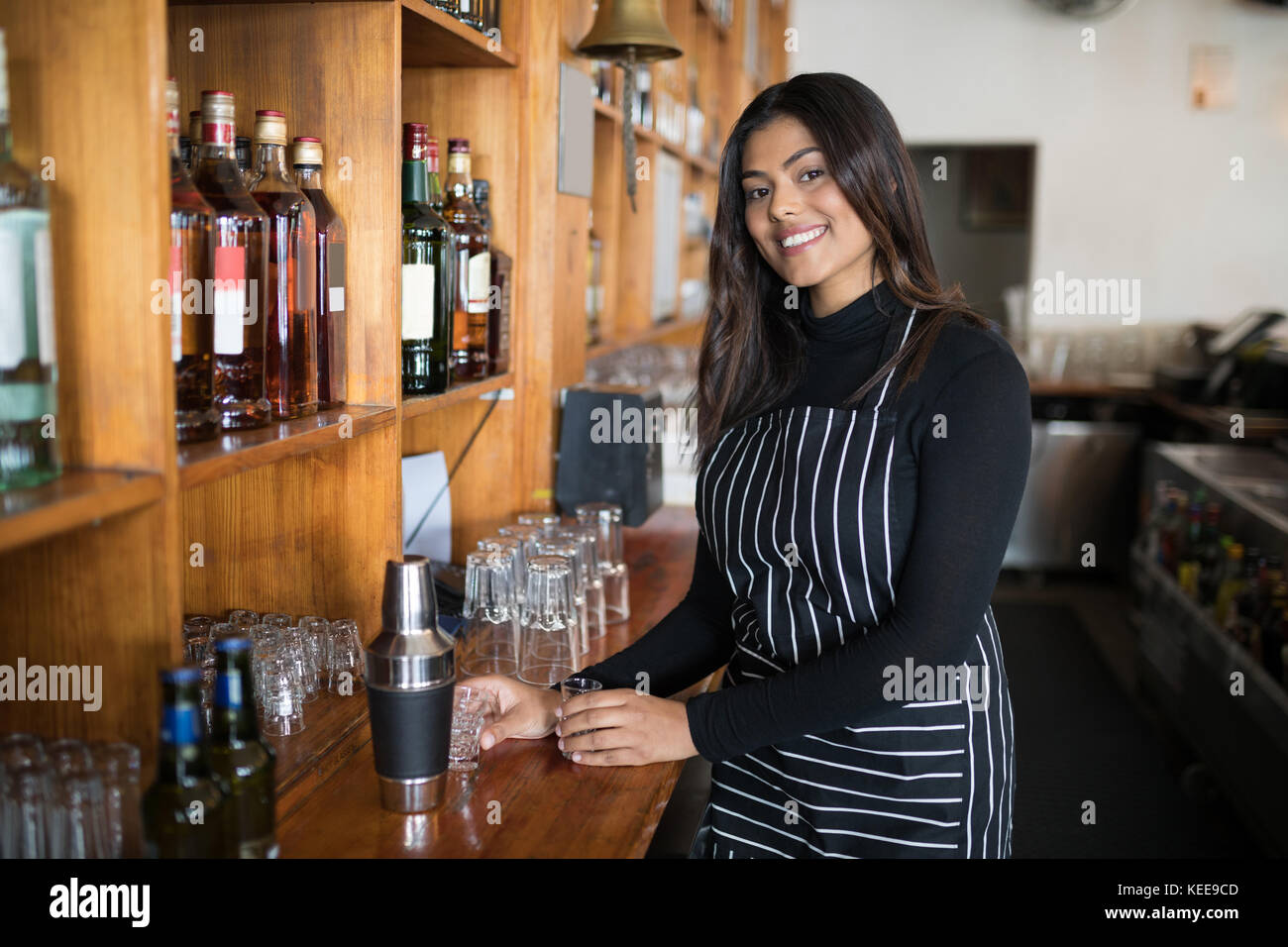 Portrait of smiling waitress standing at counter in bar Stock Photo - Alamy