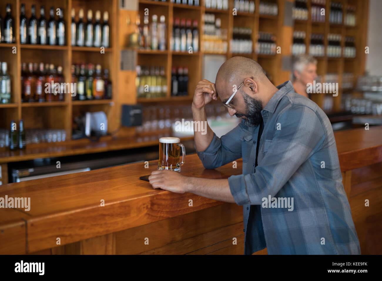 Depressed man standing at counter in bar Stock Photo - Alamy