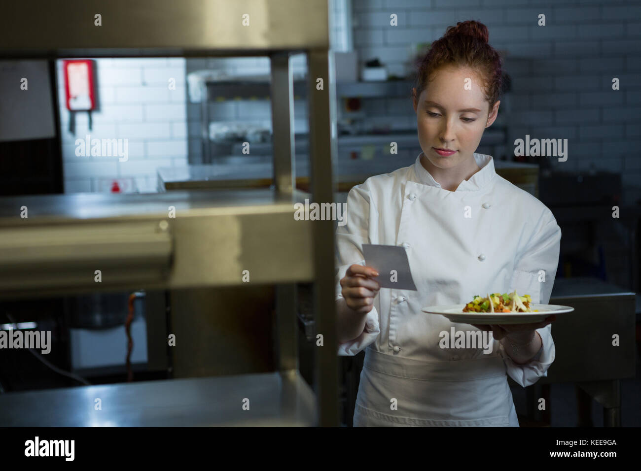 Female chef reading order in the kitchen Stock Photo - Alamy