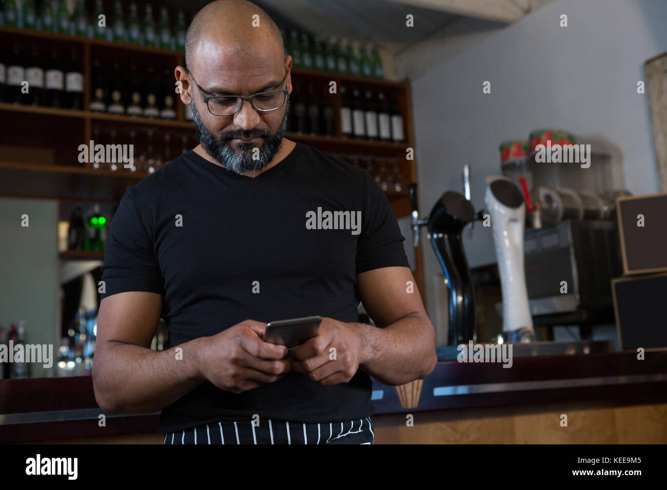 Waiter using mobile phone in the cafe Stock Photo - Alamy