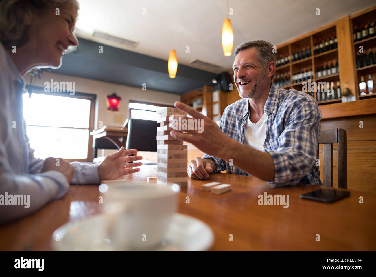 Happy senior friends playing jenga game on table in bar Stock Photo - Alamy
