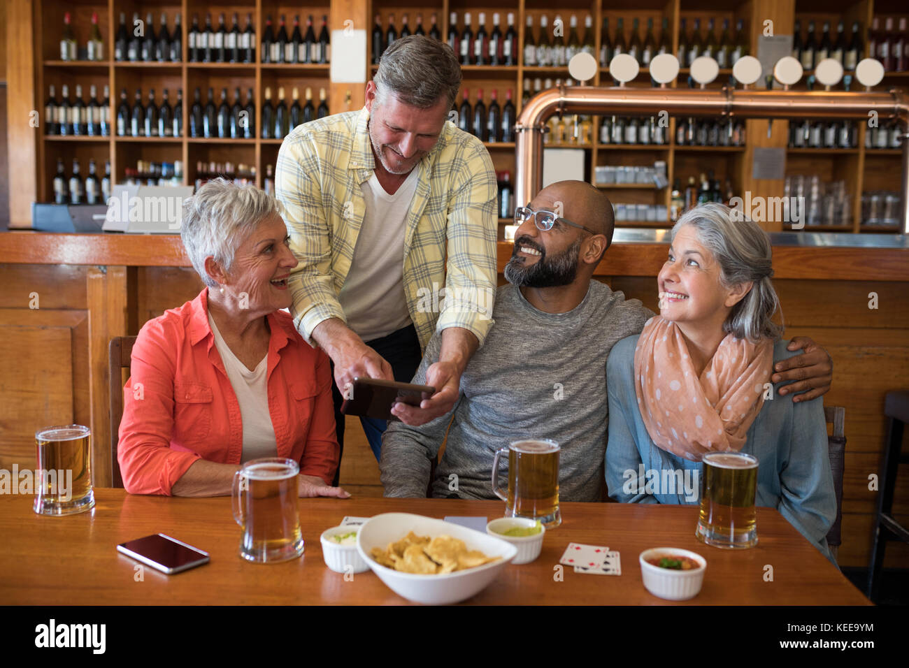 Happy friends sitting together at bar Stock Photo - Alamy