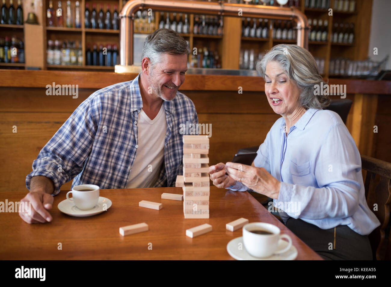 Happy senior friends playing jenga game on table in bar Stock Photo - Alamy