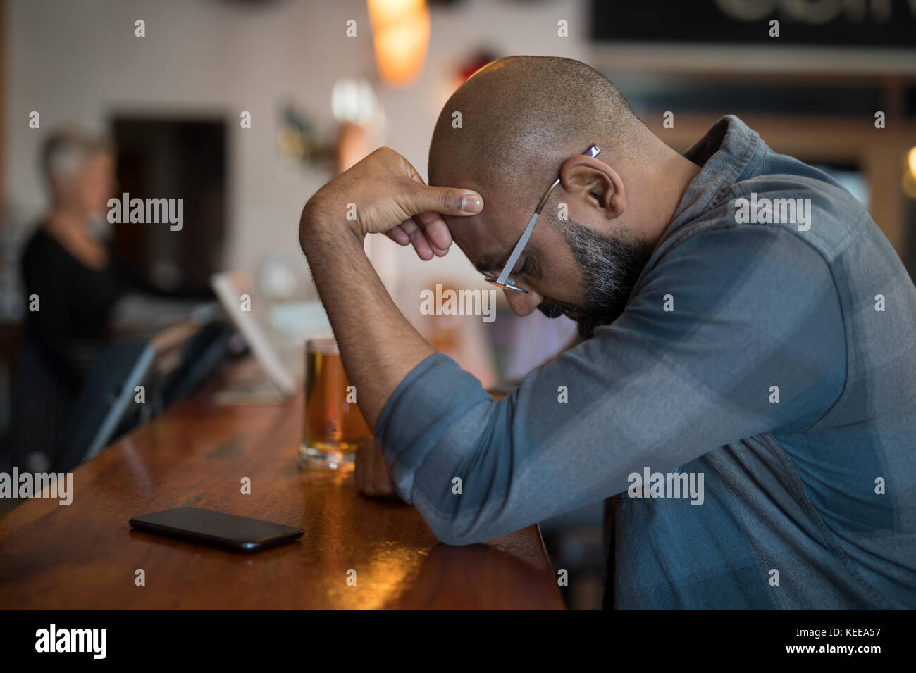Depressed man standing at counter in bar Stock Photo - Alamy