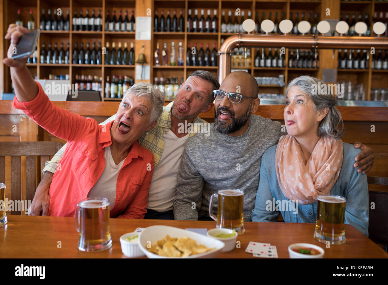 Happy friends taking selfie with mobile phone in bar Stock Photo - Alamy
