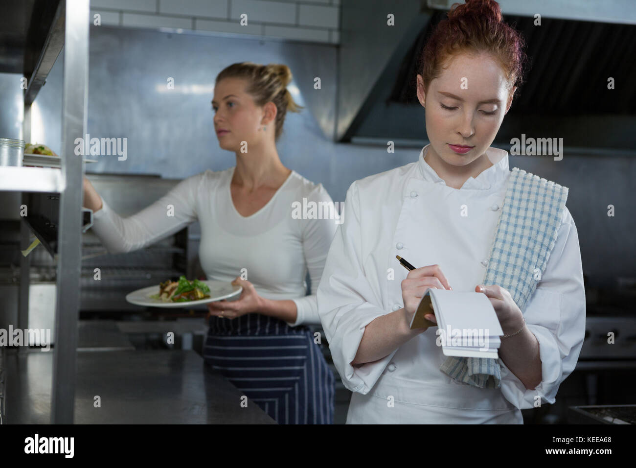 Female writing in the notepad in the kitchen Stock Photo - Alamy