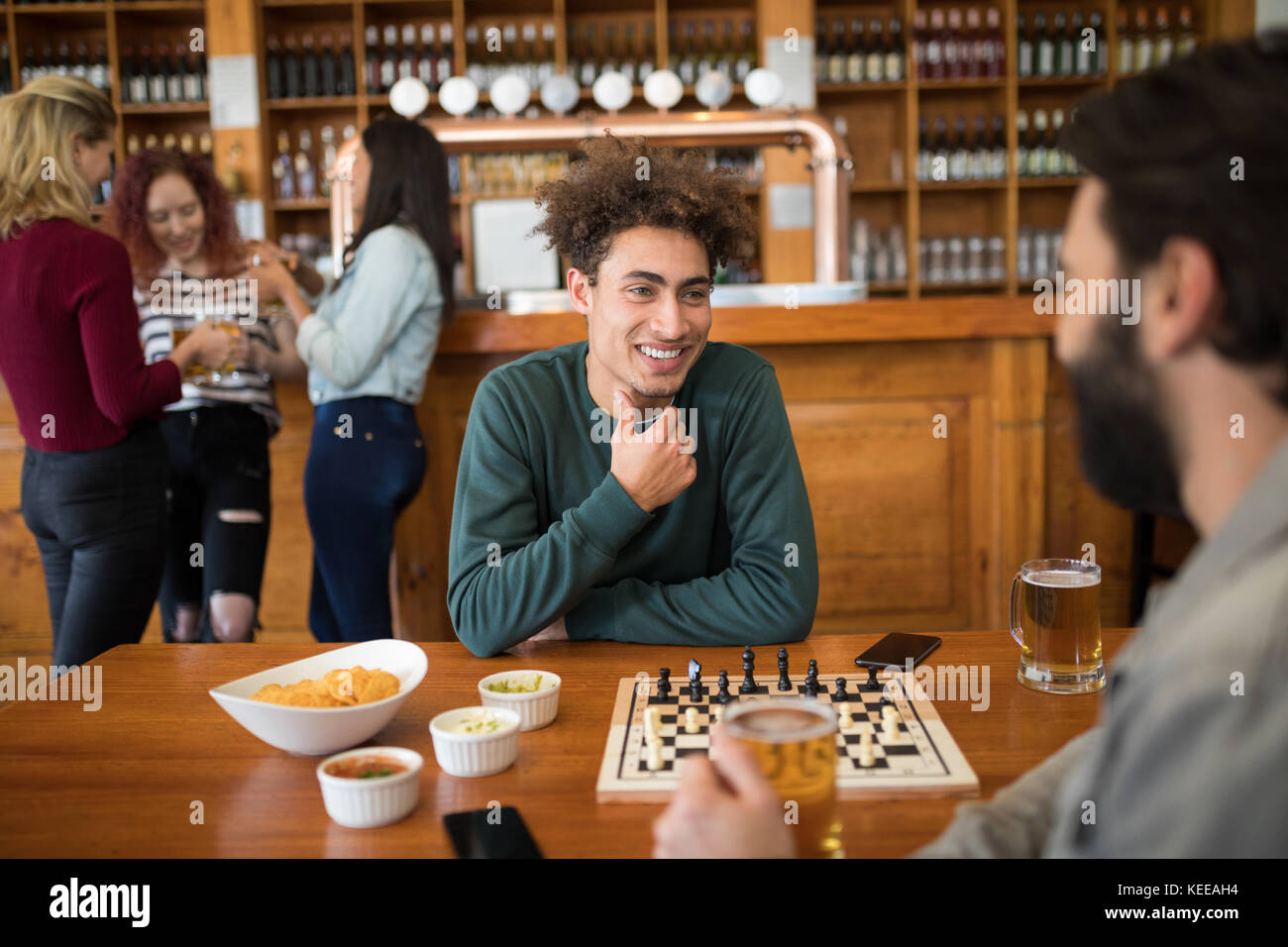 Two men playing chess while having glass of beer in bar Stock Photo - Alamy
