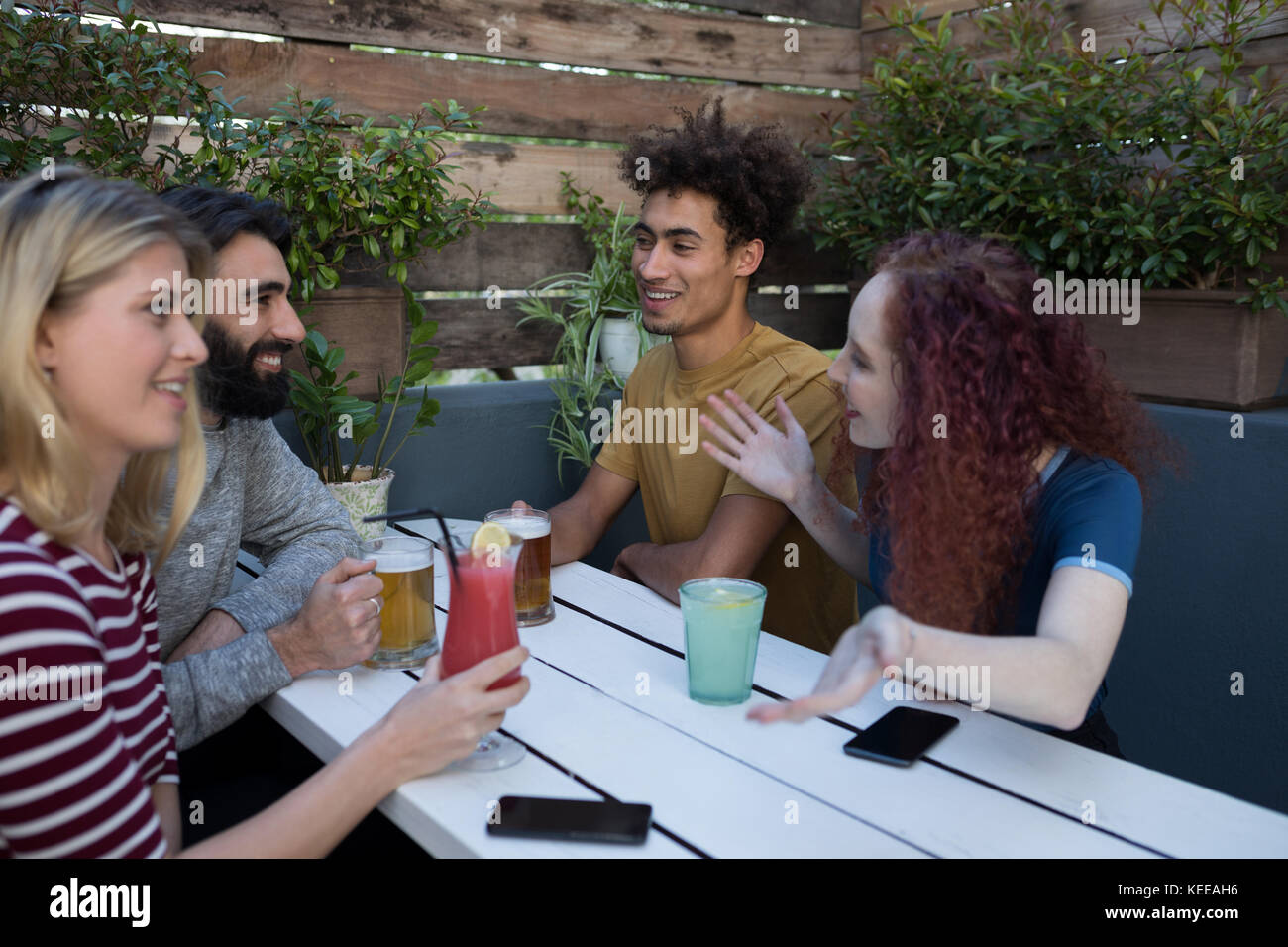 Friends interacting while having glass of drinks in bar Stock Photo - Alamy