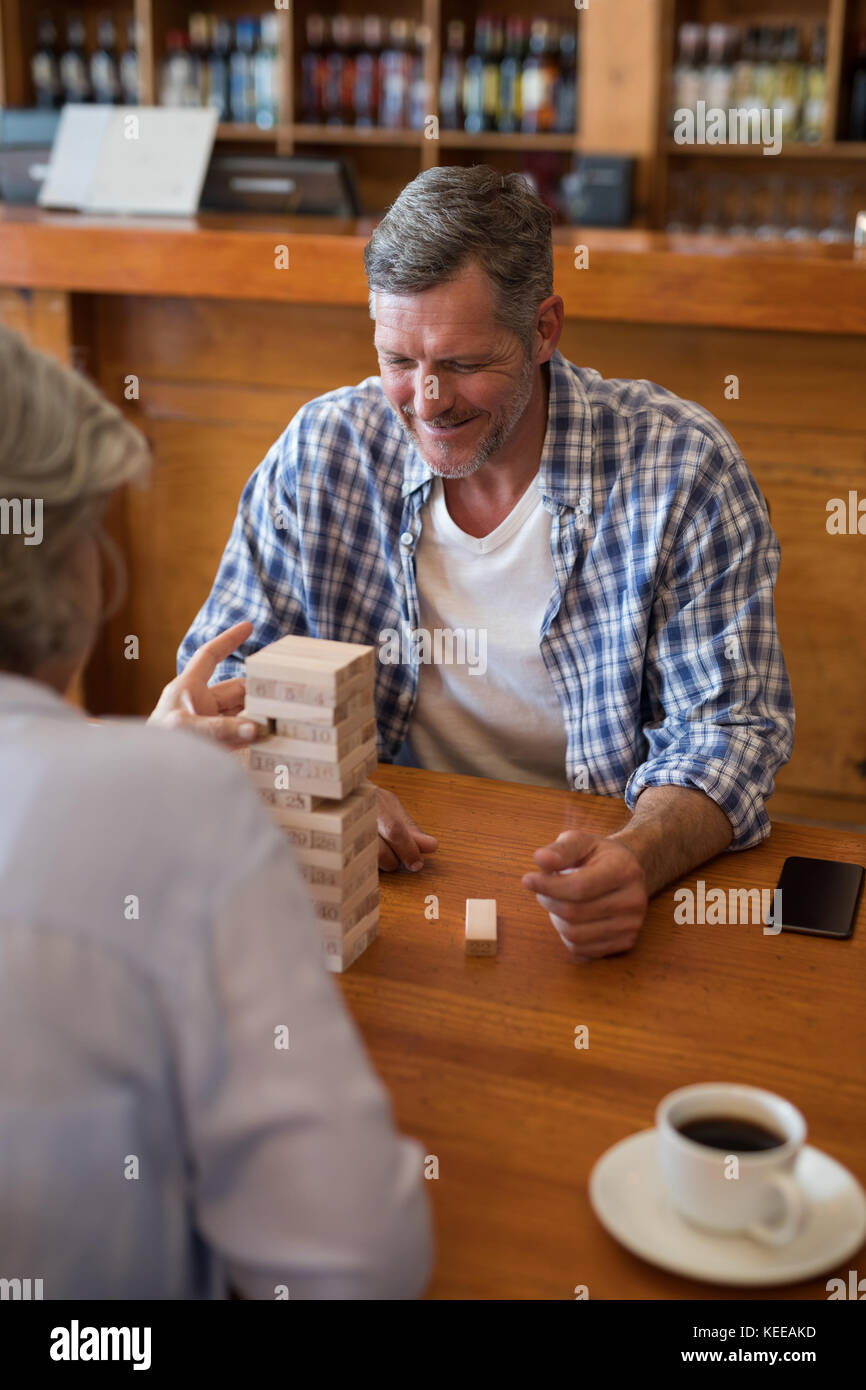 Happy senior friends playing jenga game on table in bar Stock Photo - Alamy