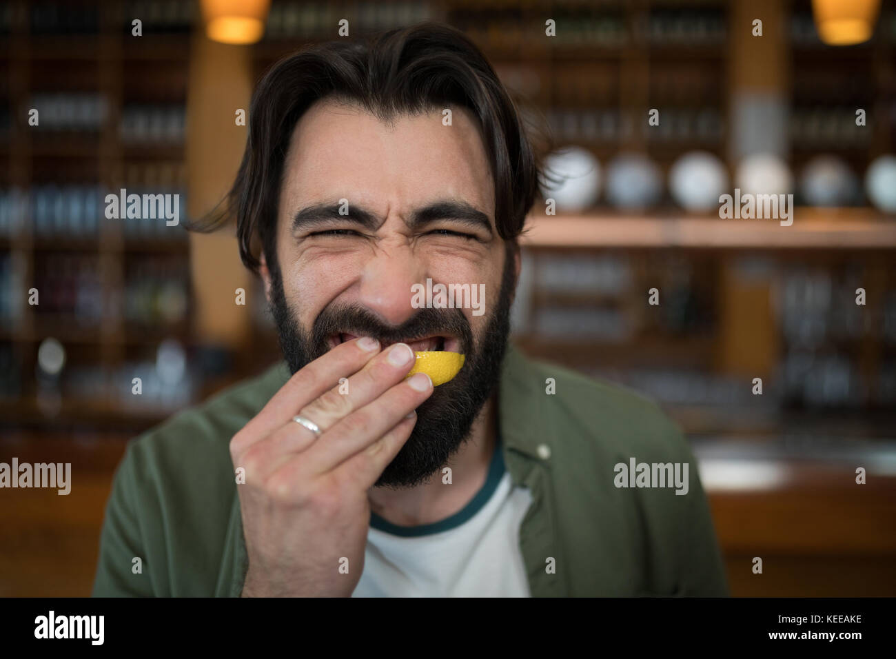 Man biting into lemon wedge after having tequila shot in bar Stock ...