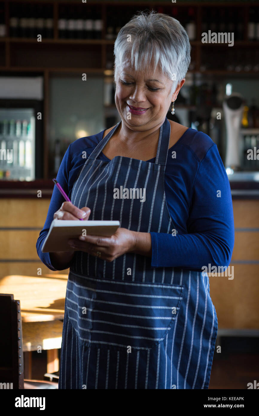 Waitress writing an order in the notepad in the bar Stock Photo - Alamy
