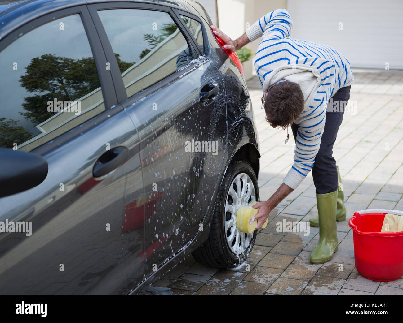 Male auto service staff washing a car tyre with sponge Stock Photo - Alamy