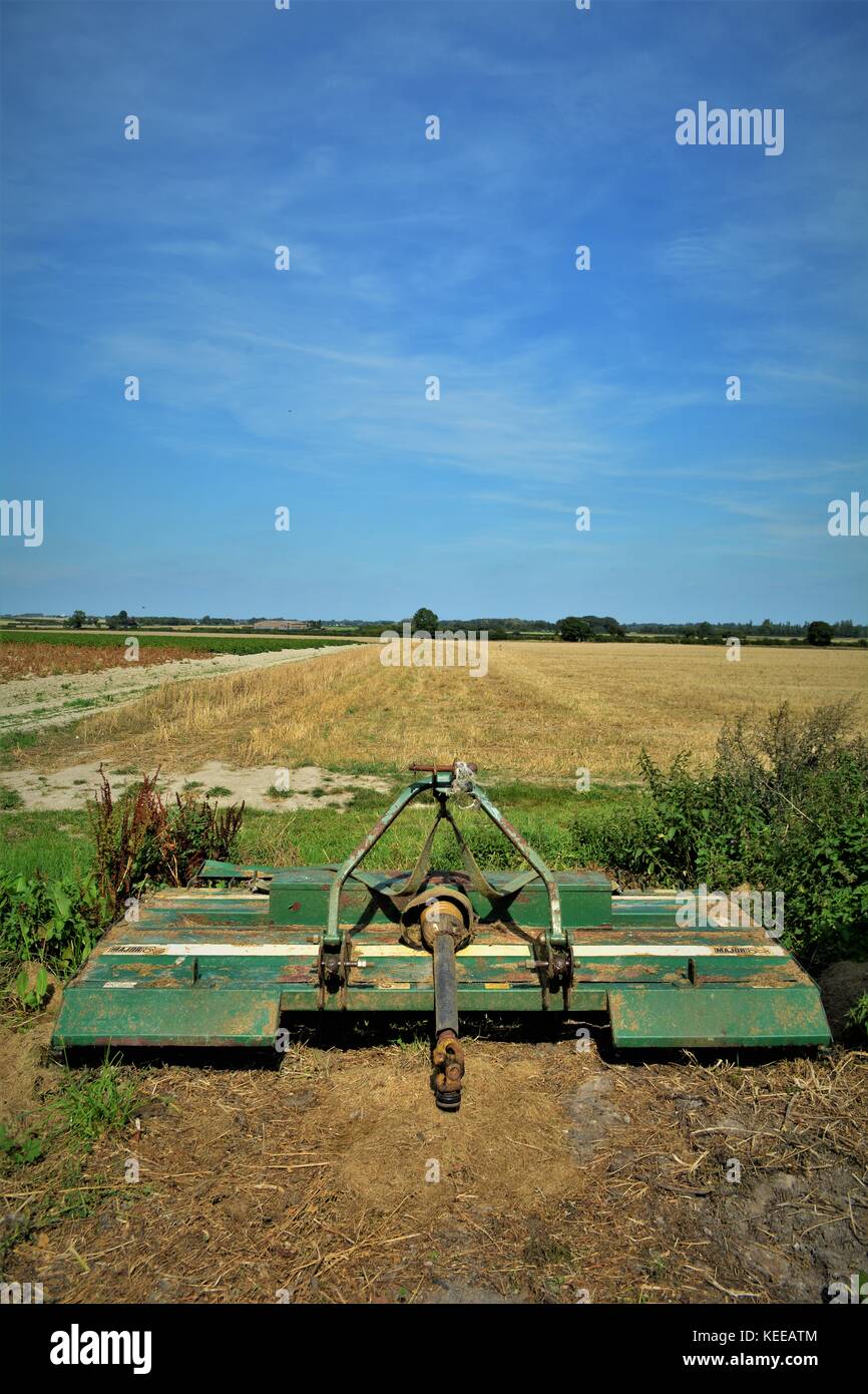 green farm machine waiting beside field for use Stock Photo - Alamy