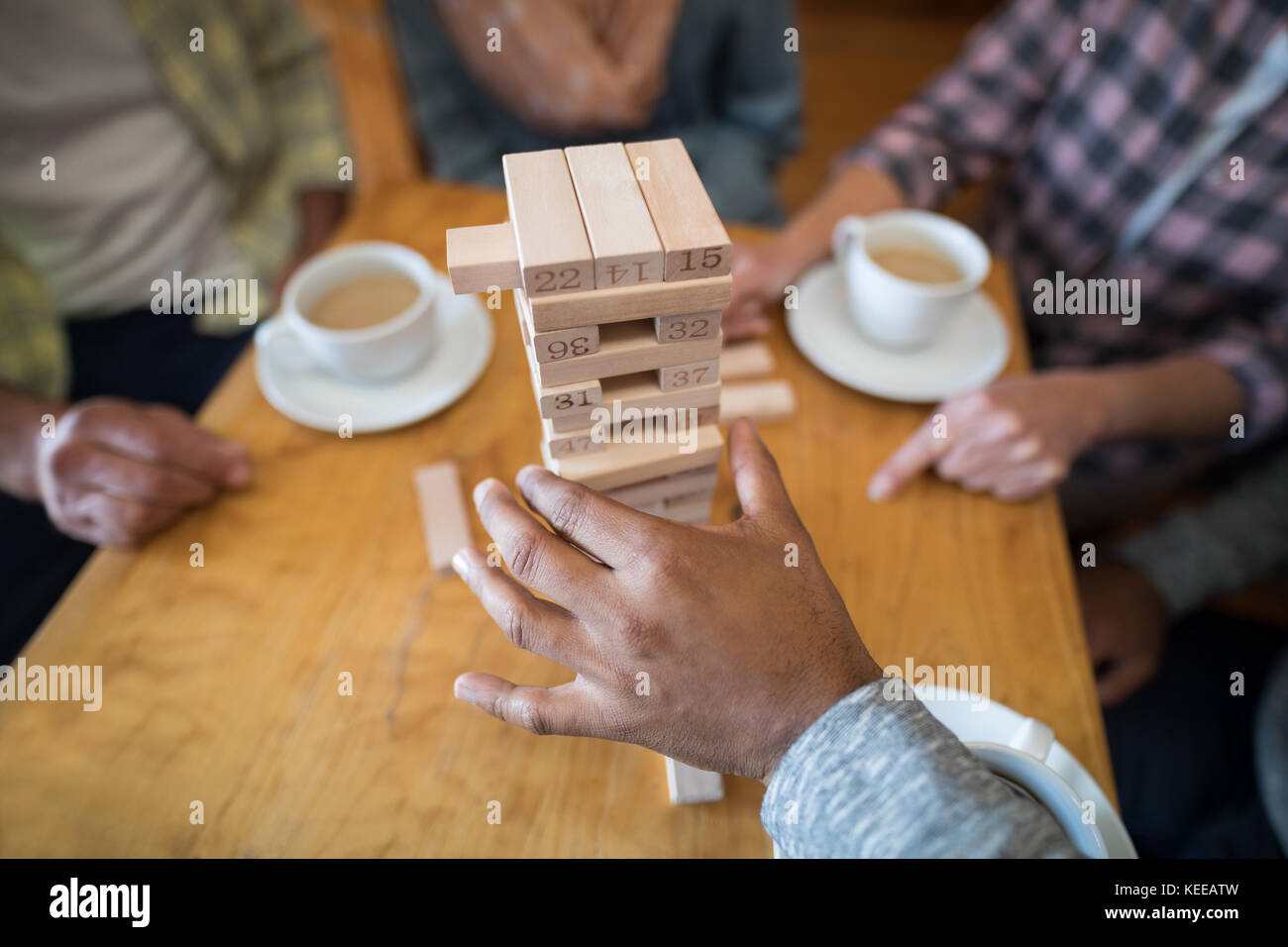 Mid section of senior friends playing jenga game on table in bar Stock ...