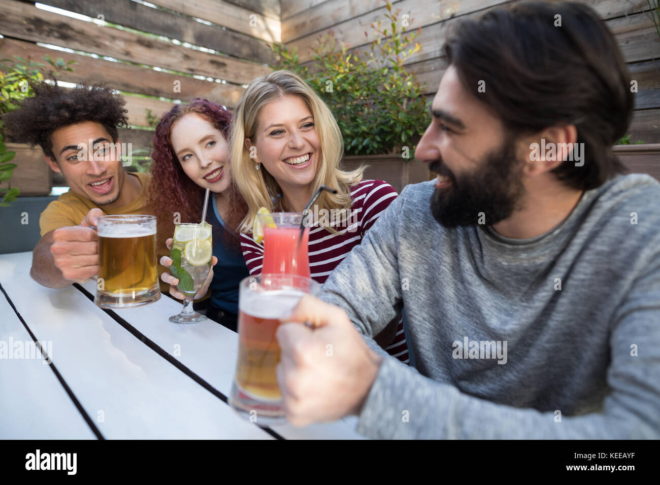 Friends interacting while having glass of drinks in bar Stock Photo - Alamy