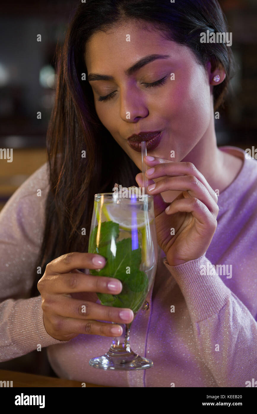 Beautiful woman sipping on a drink Stock Photo - Alamy
