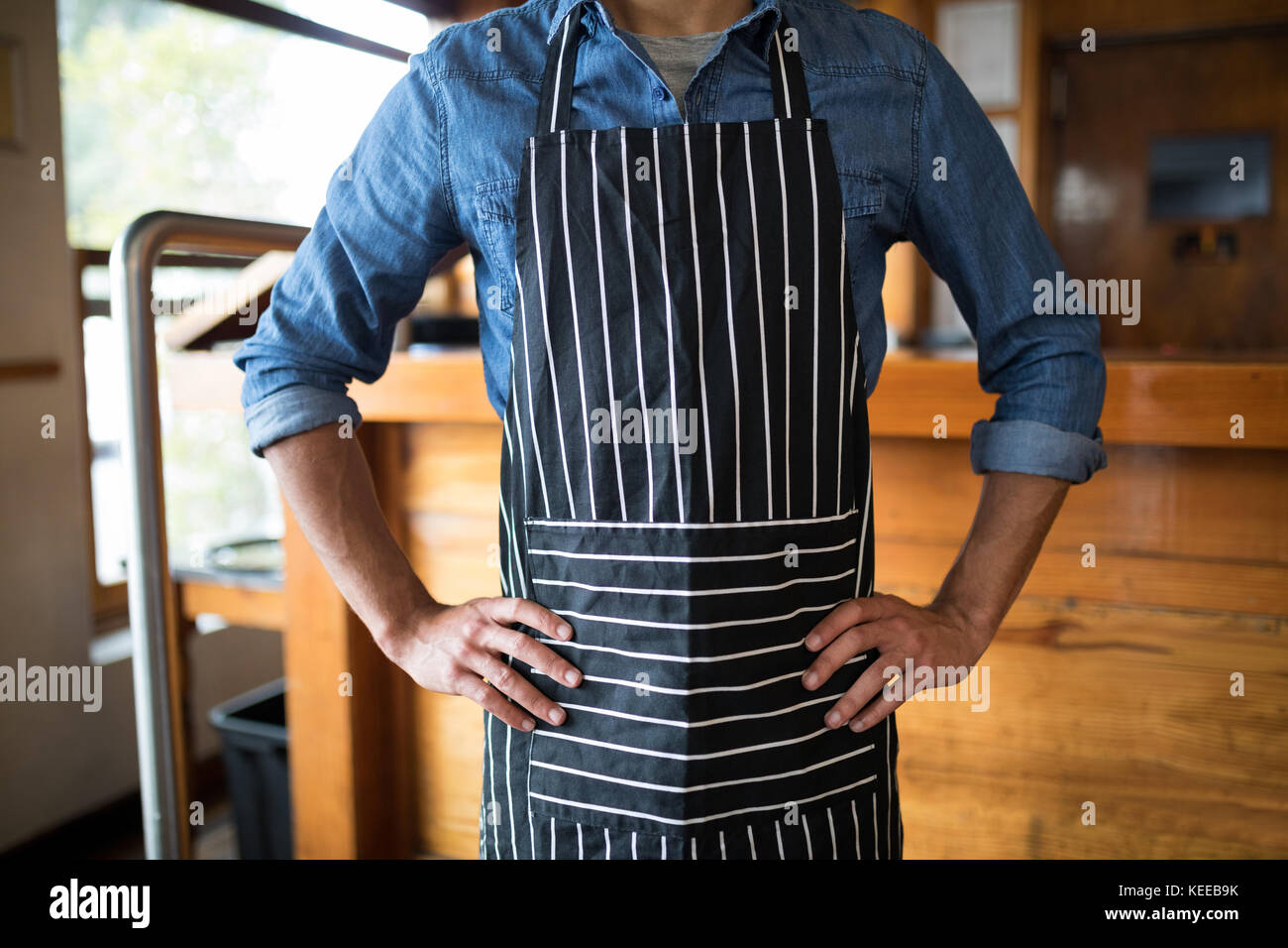 Mid section of waiter standing with hands on hip in bar Stock Photo - Alamy