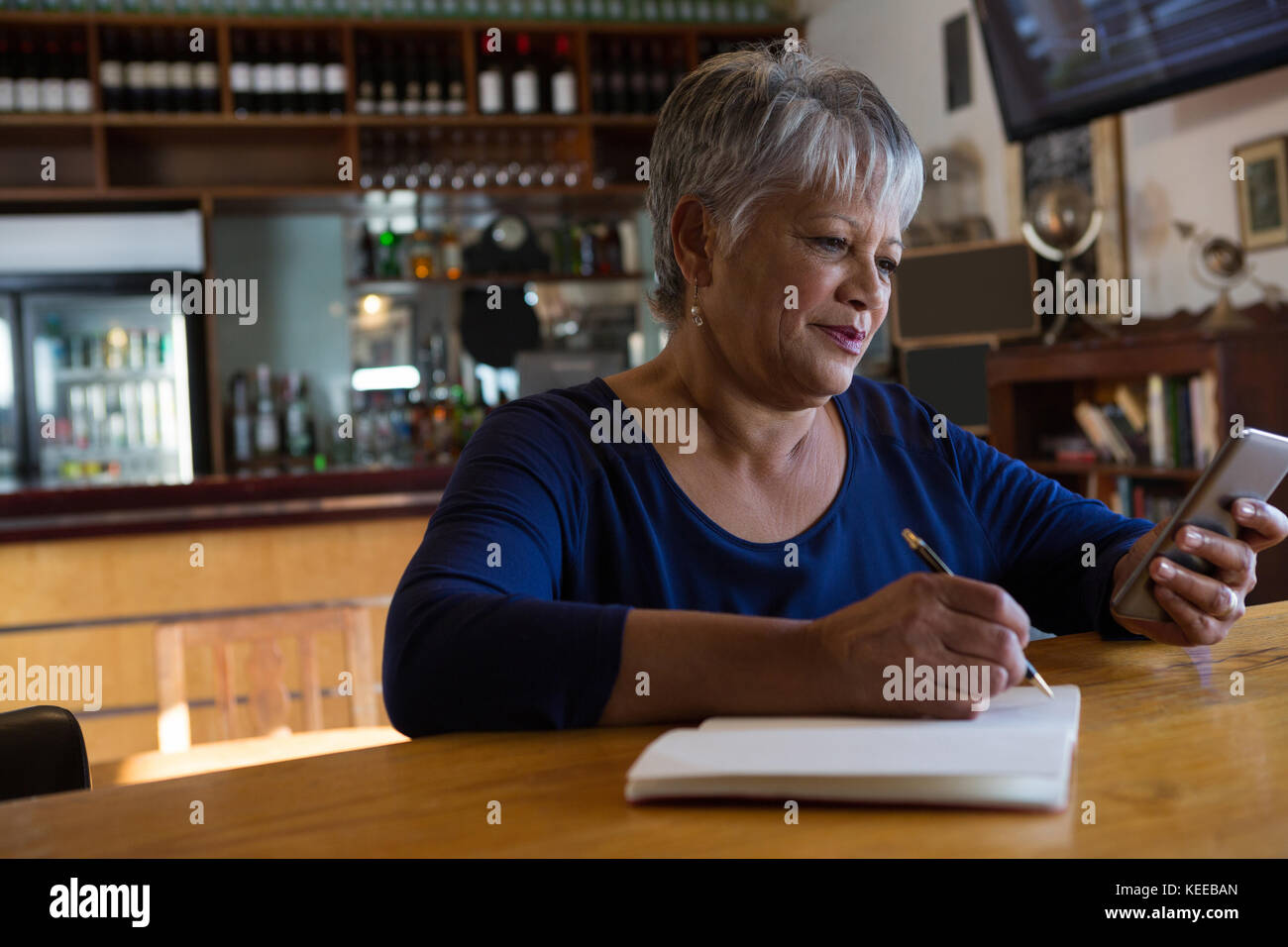 Waitress using her mobilephone near cafe counter Stock Photo - Alamy