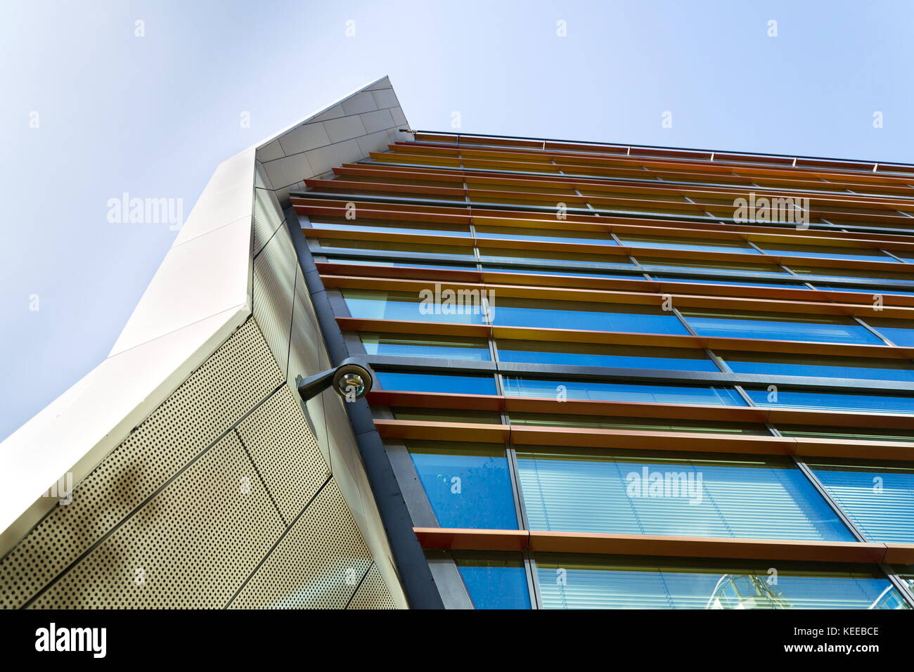 Modern security camera attached to wall with windows in background ...