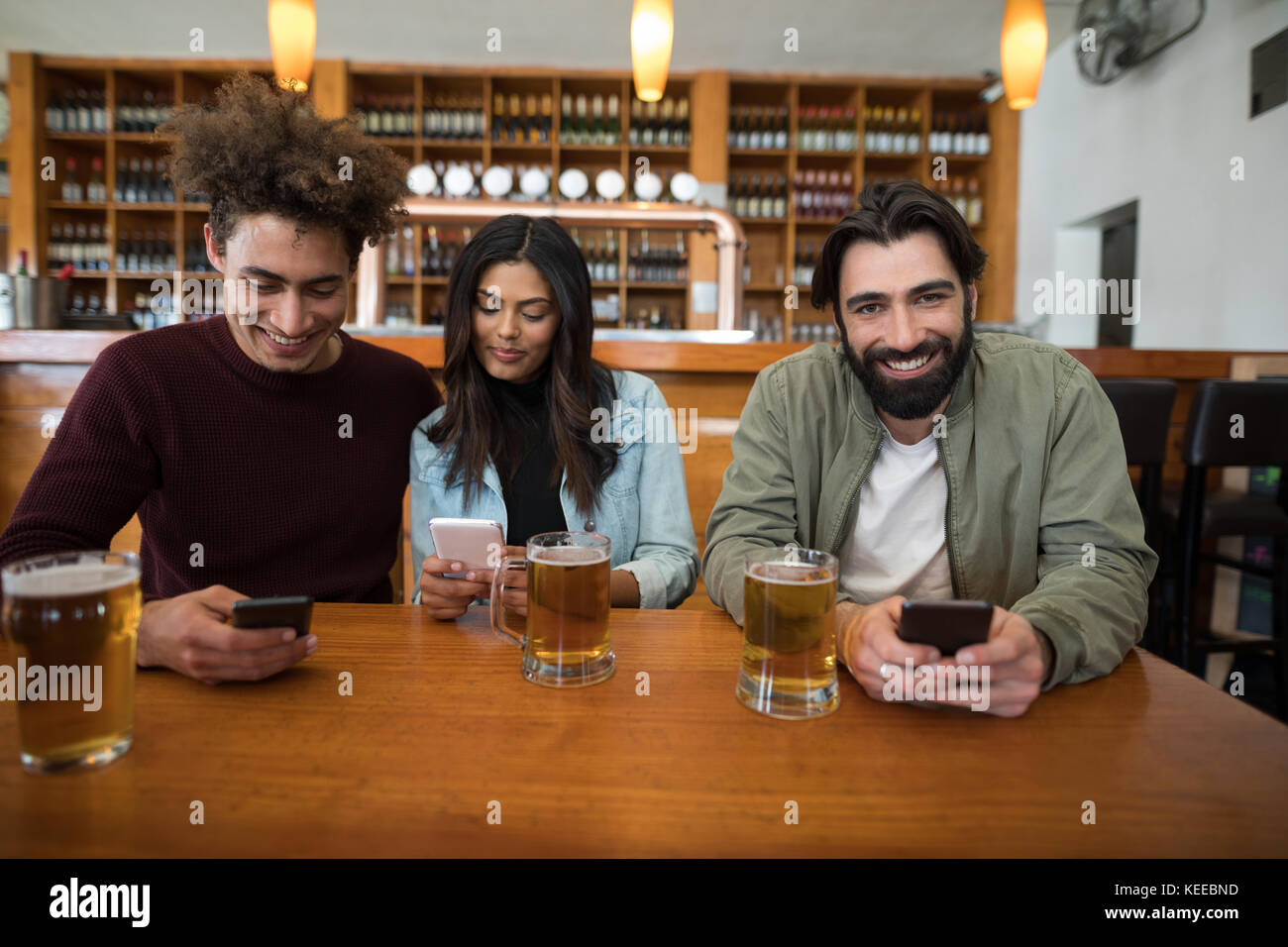 Friends using mobile phone on table in bar Stock Photo - Alamy