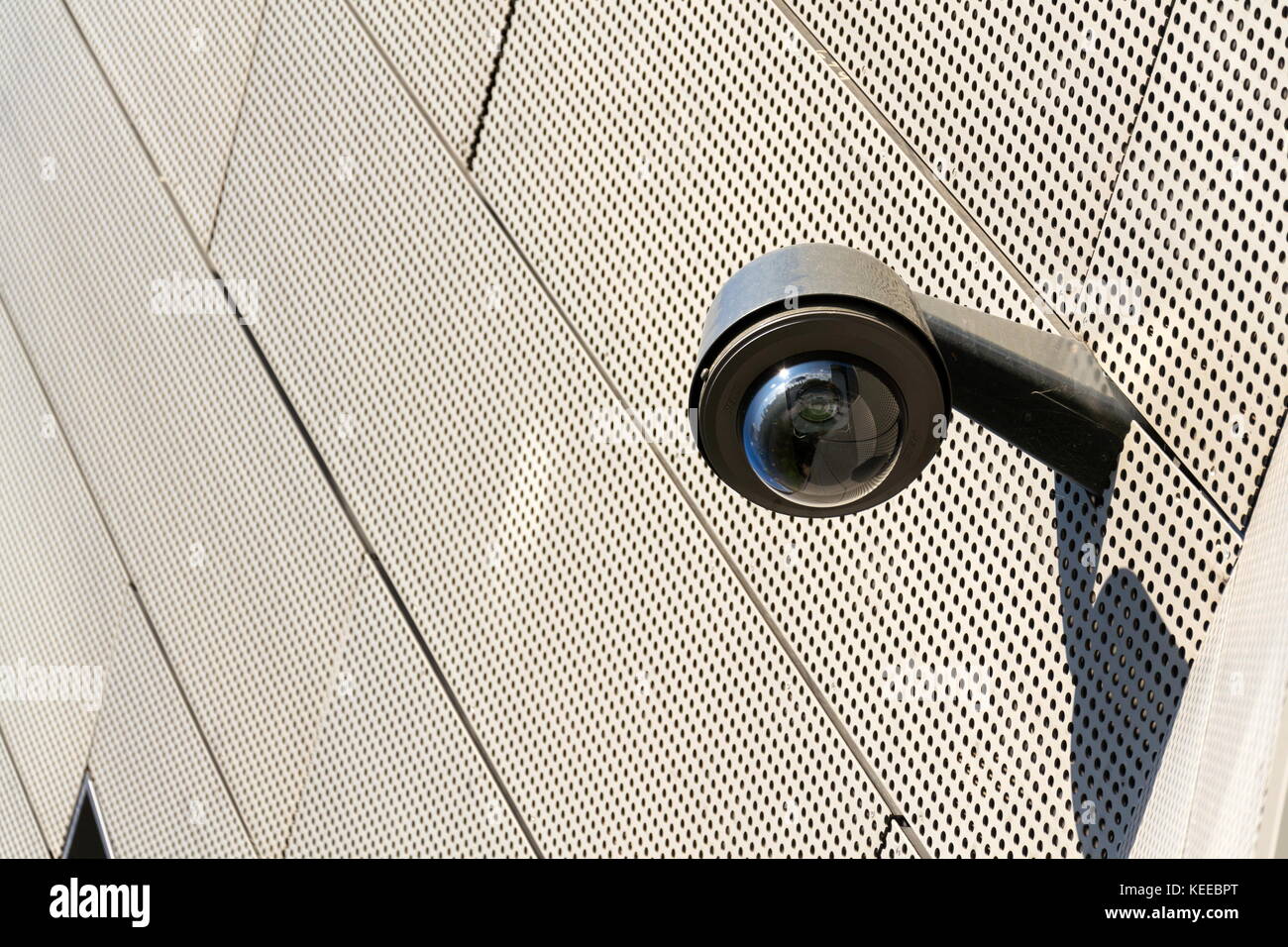 Modern security camera attached to wall with windows in background ...