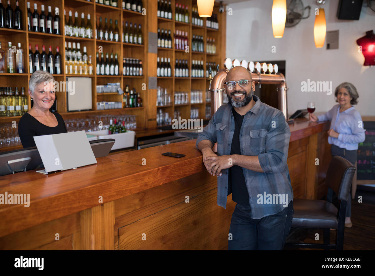 Smiling man and senior waitress looking at camera in bar Stock Photo ...