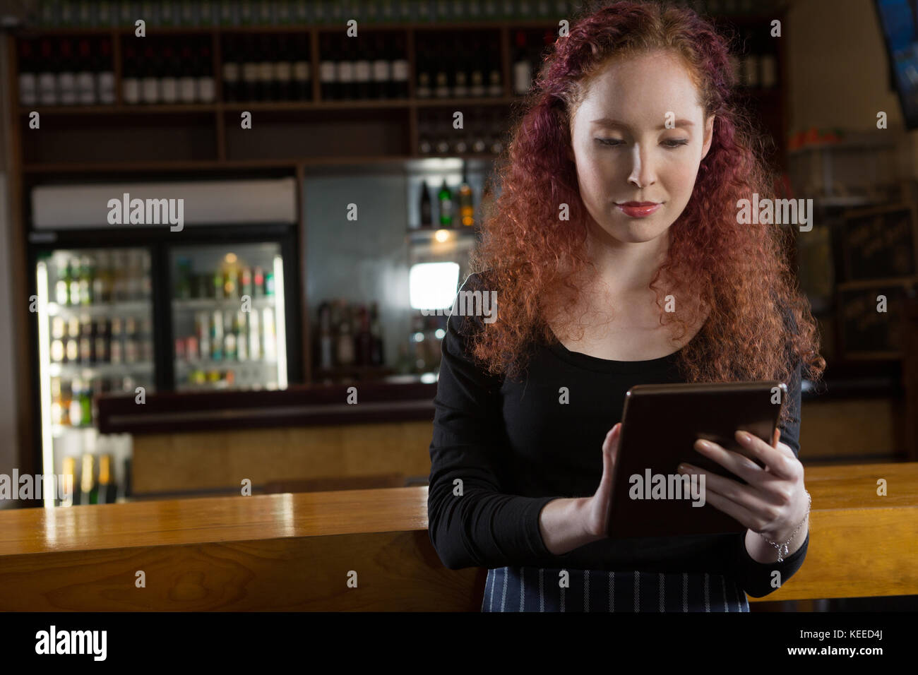 Beautiful waitress using digital tablet near bar counter Stock Photo ...