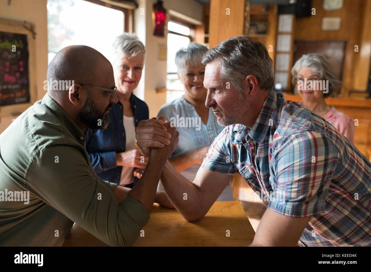 Happy friend arm wrestling each other in a bar Stock Photo - Alamy