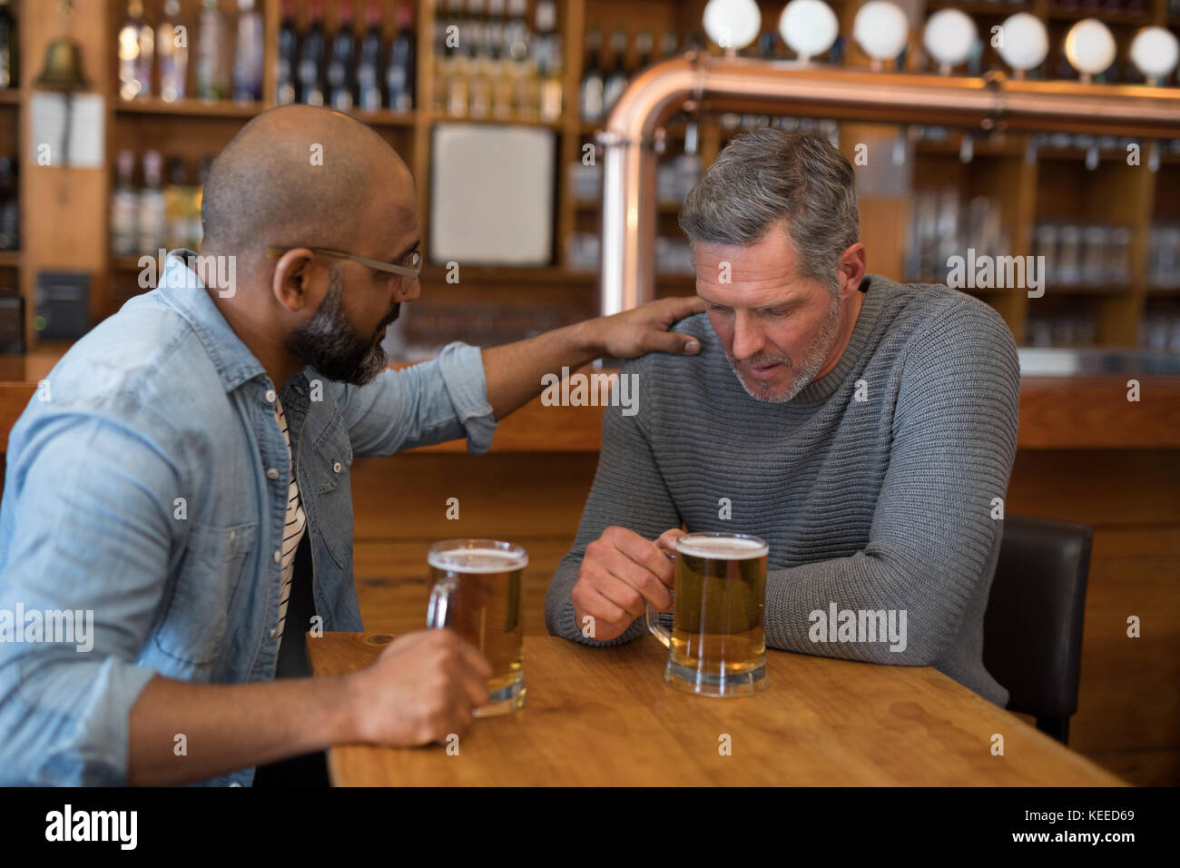 Man comforting his depressed friend in restaurant Stock Photo - Alamy