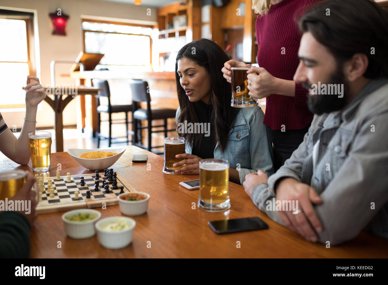 Smiling friends playing chess while having glass of beer in bar Stock ...