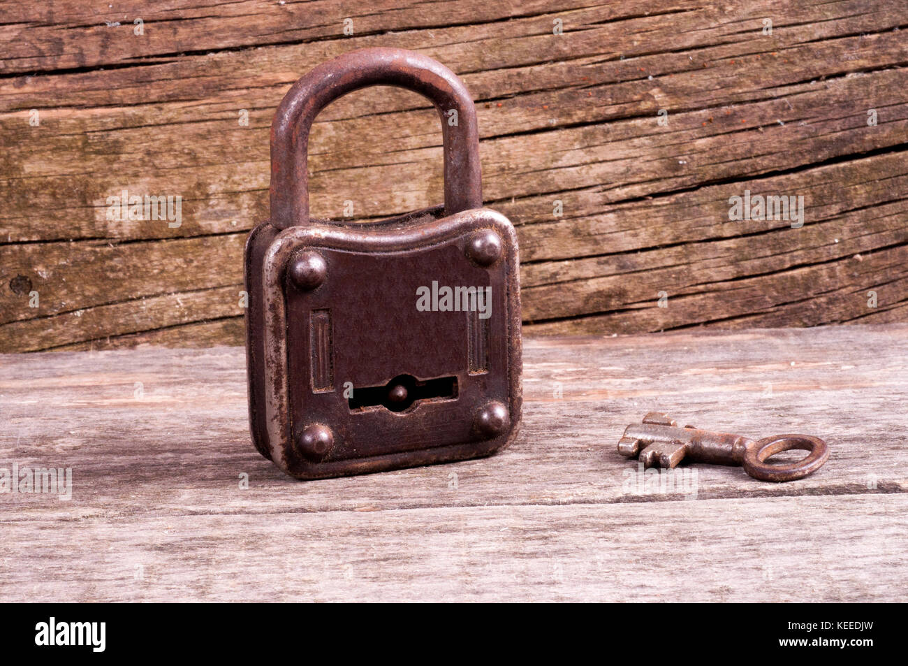 Grungy steel metal key and rusted lock on a old wooden boards ...