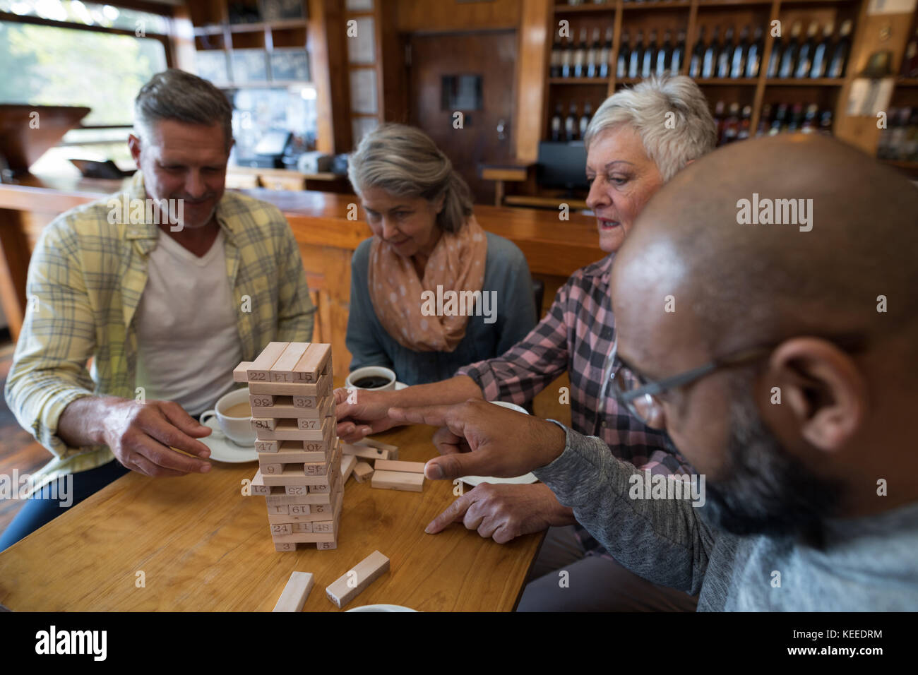 Happy friends playing jenga game while having cup of coffee in bar ...