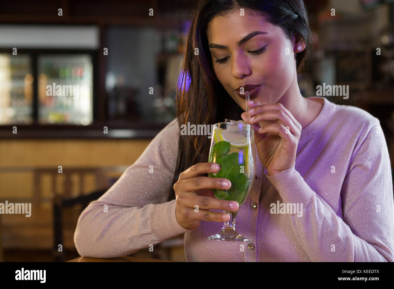 Beautiful woman sipping on a drink Stock Photo - Alamy