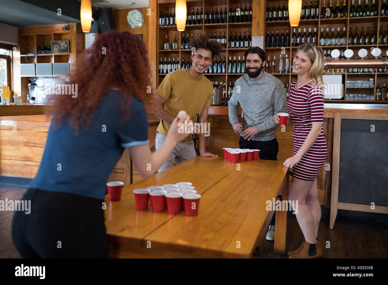 Smiling friends playing beer pong on table in bar Stock Photo - Alamy