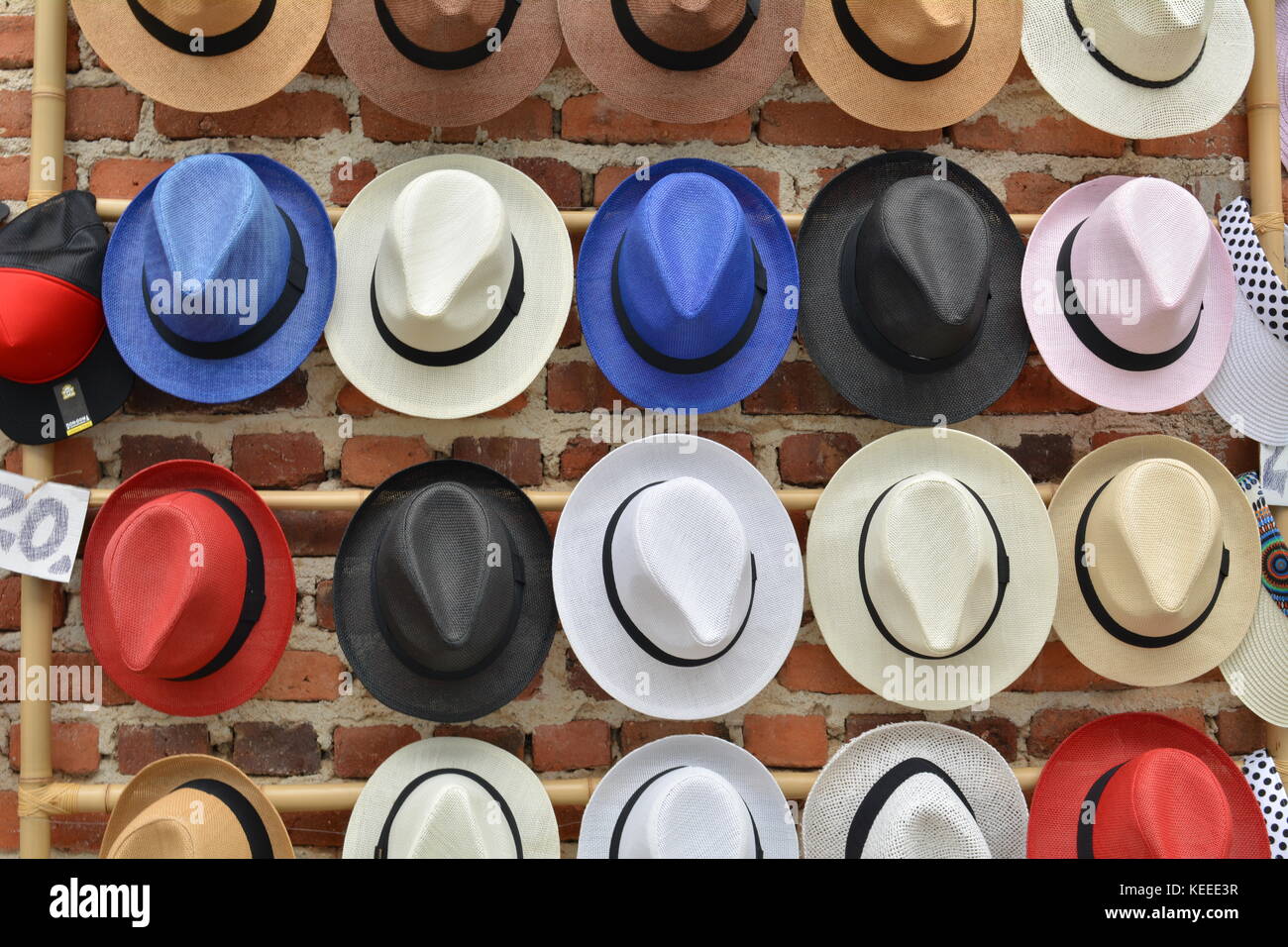 hats of various colors hanging on a brick wall Stock Photo - Alamy