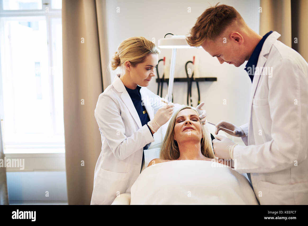 Young doctor and his assistant preparing a botox treatment around the ...