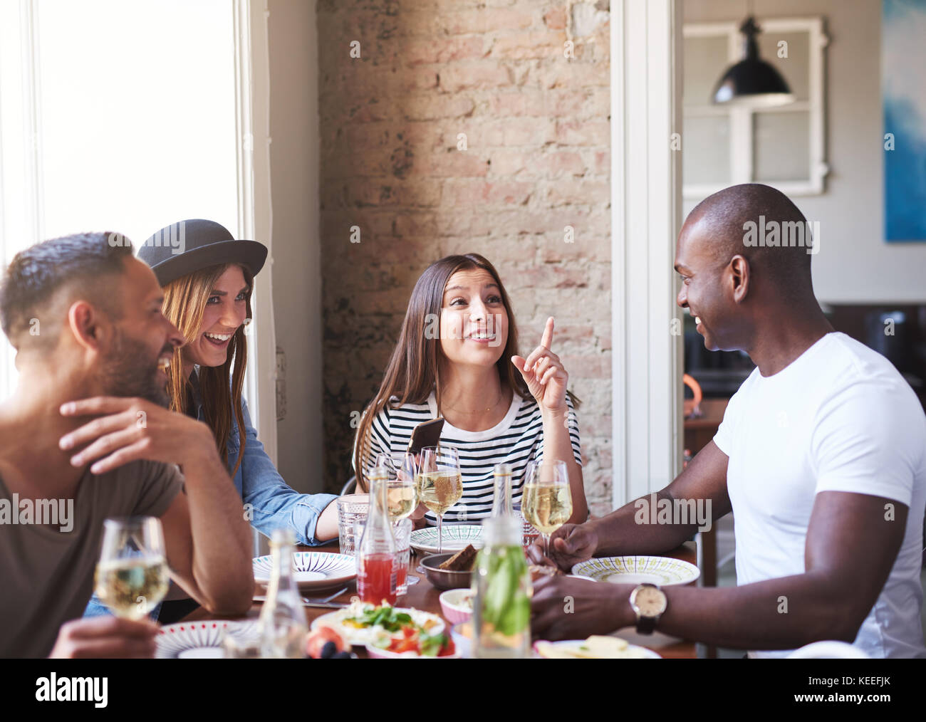 Diverse small group of four happy friends having wine and dinner ...