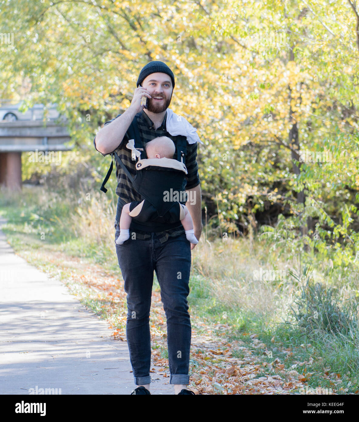 Millennial Dad with Baby in Carrier Outside Talking and Texting Stock ...